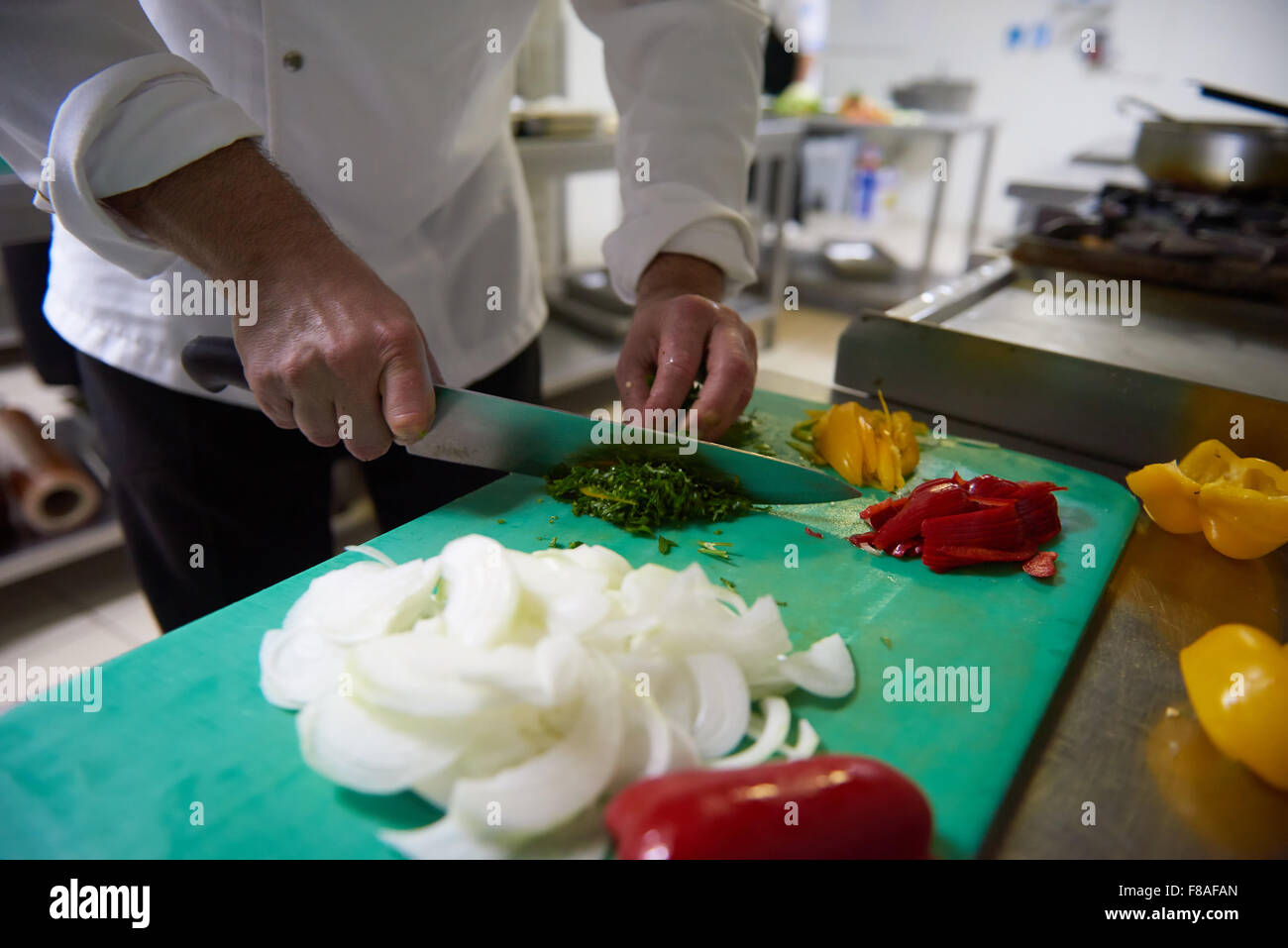 chef in hotel kitchen slice vegetables with knife and prepare food ...