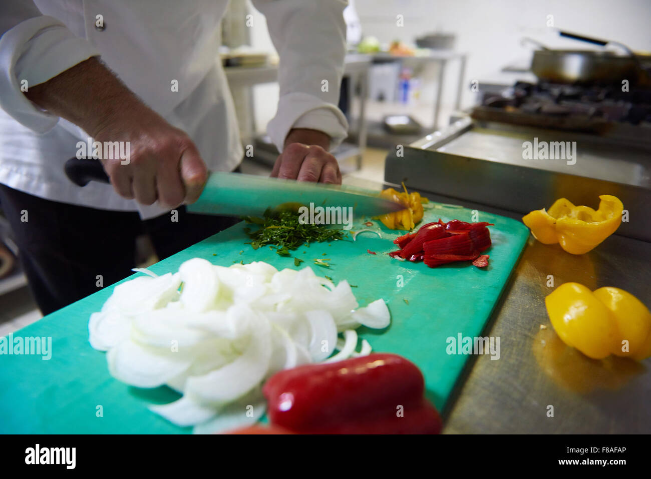 chef in hotel kitchen slice vegetables with knife and prepare food ...