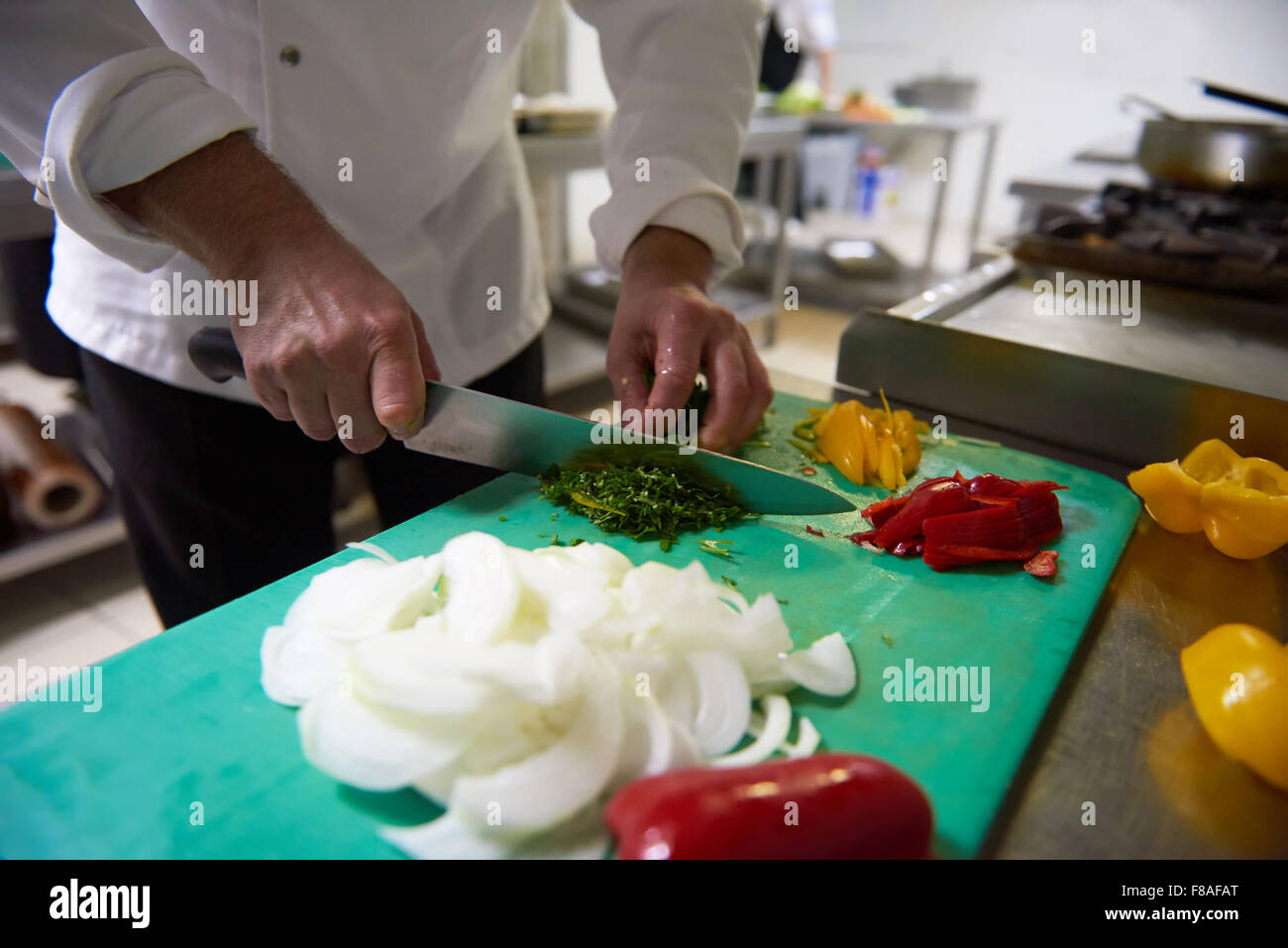 chef in hotel kitchen slice vegetables with knife and prepare food ...