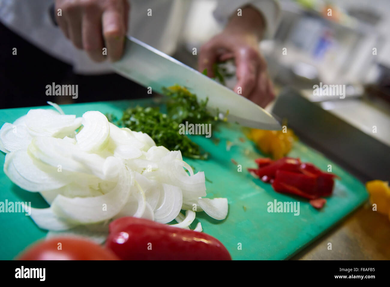 chef in hotel kitchen slice vegetables with knife and prepare food ...