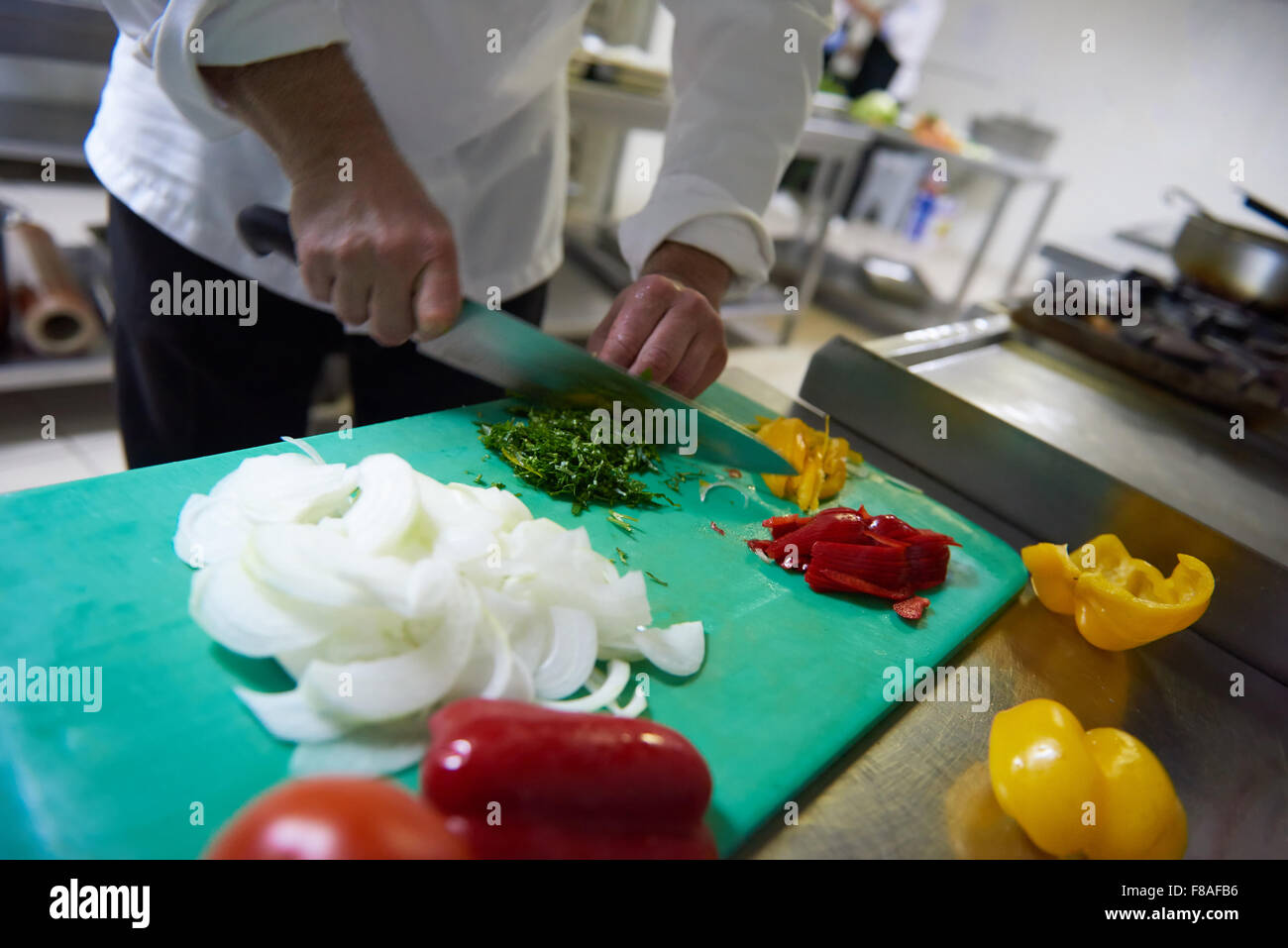 chef in hotel kitchen slice vegetables with knife and prepare food ...