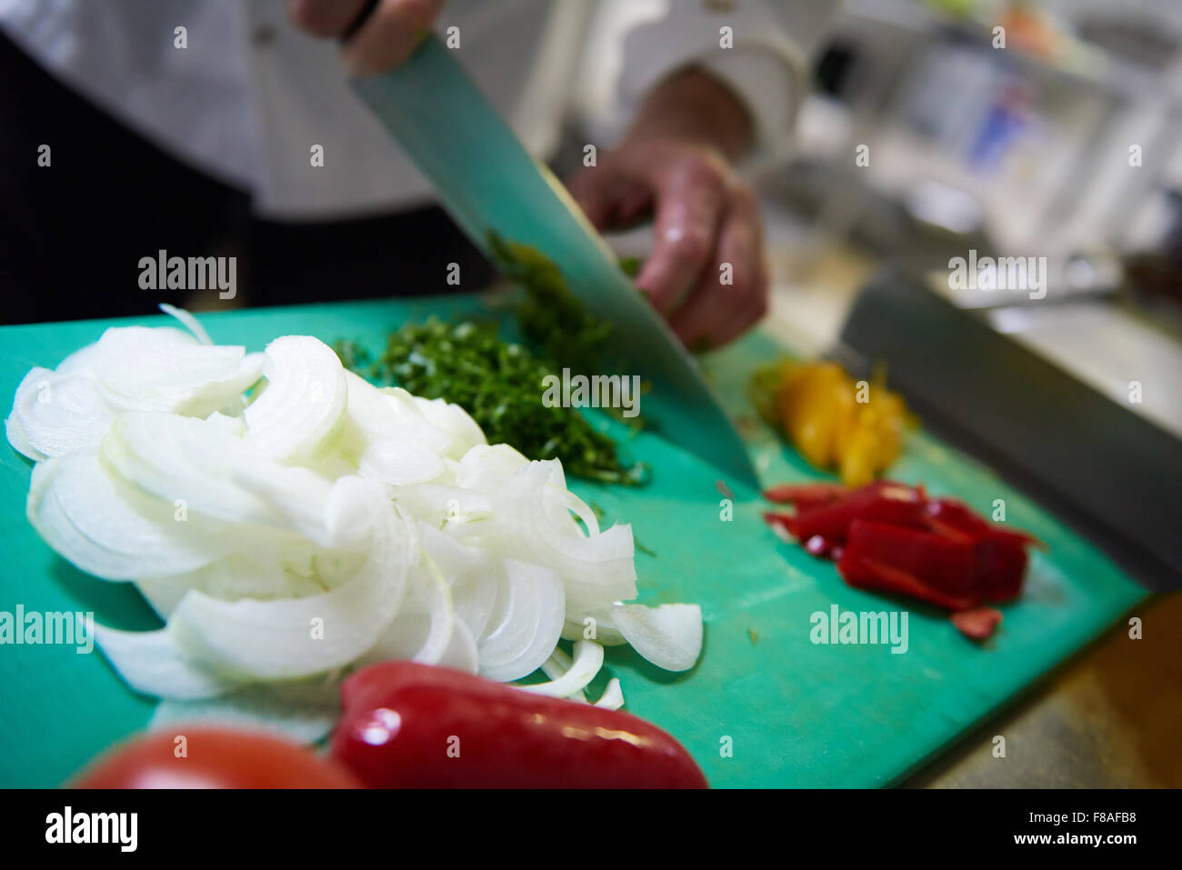 chef in hotel kitchen slice vegetables with knife and prepare food ...