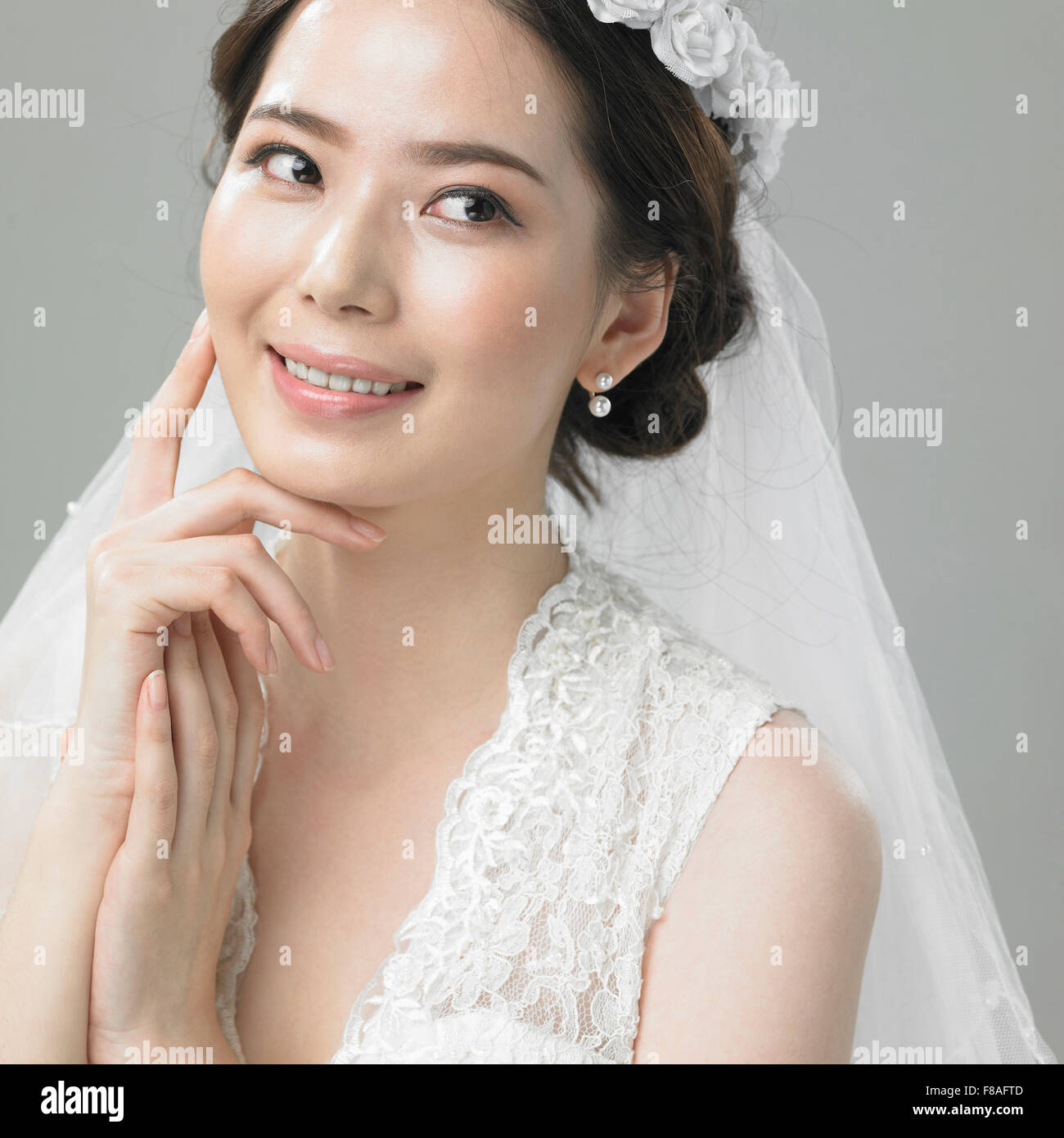 Smiling Korean bride in wedding veil with two hands together Stock ...