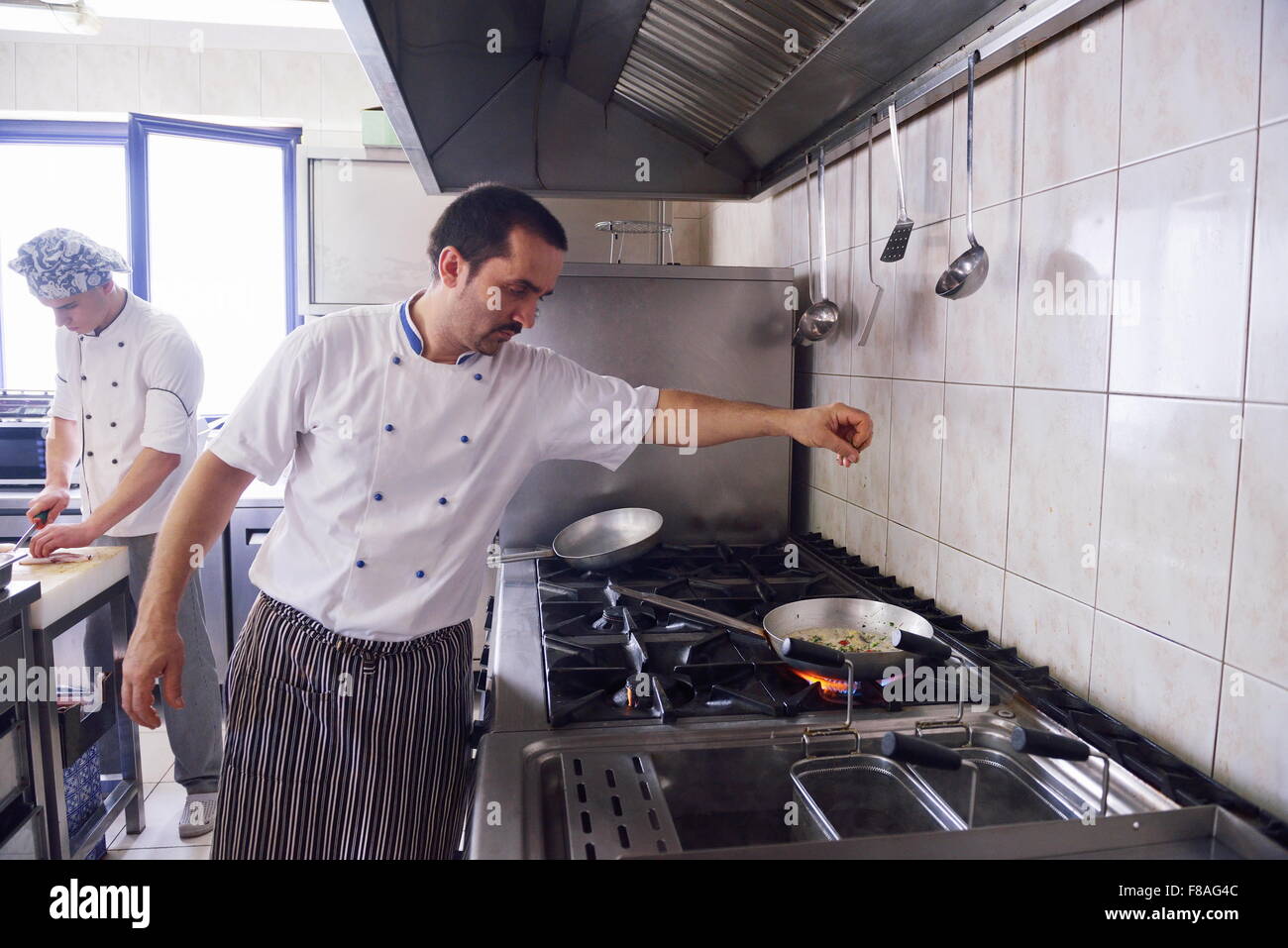 Handsome chef dressed in white uniform decorating pasta salad and ...