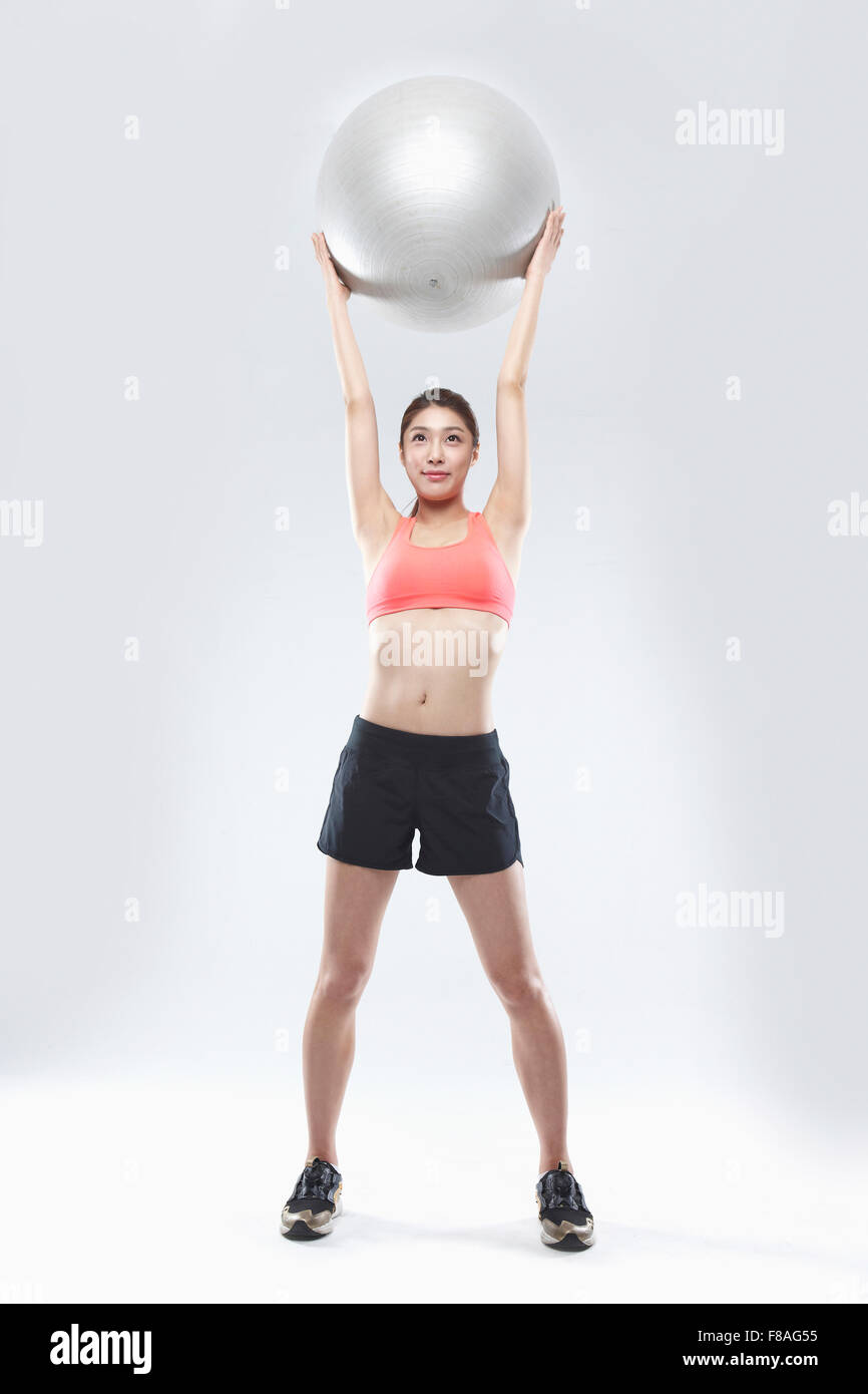 Woman in sportswear lifting up gym ball high above her head Stock Photo ...