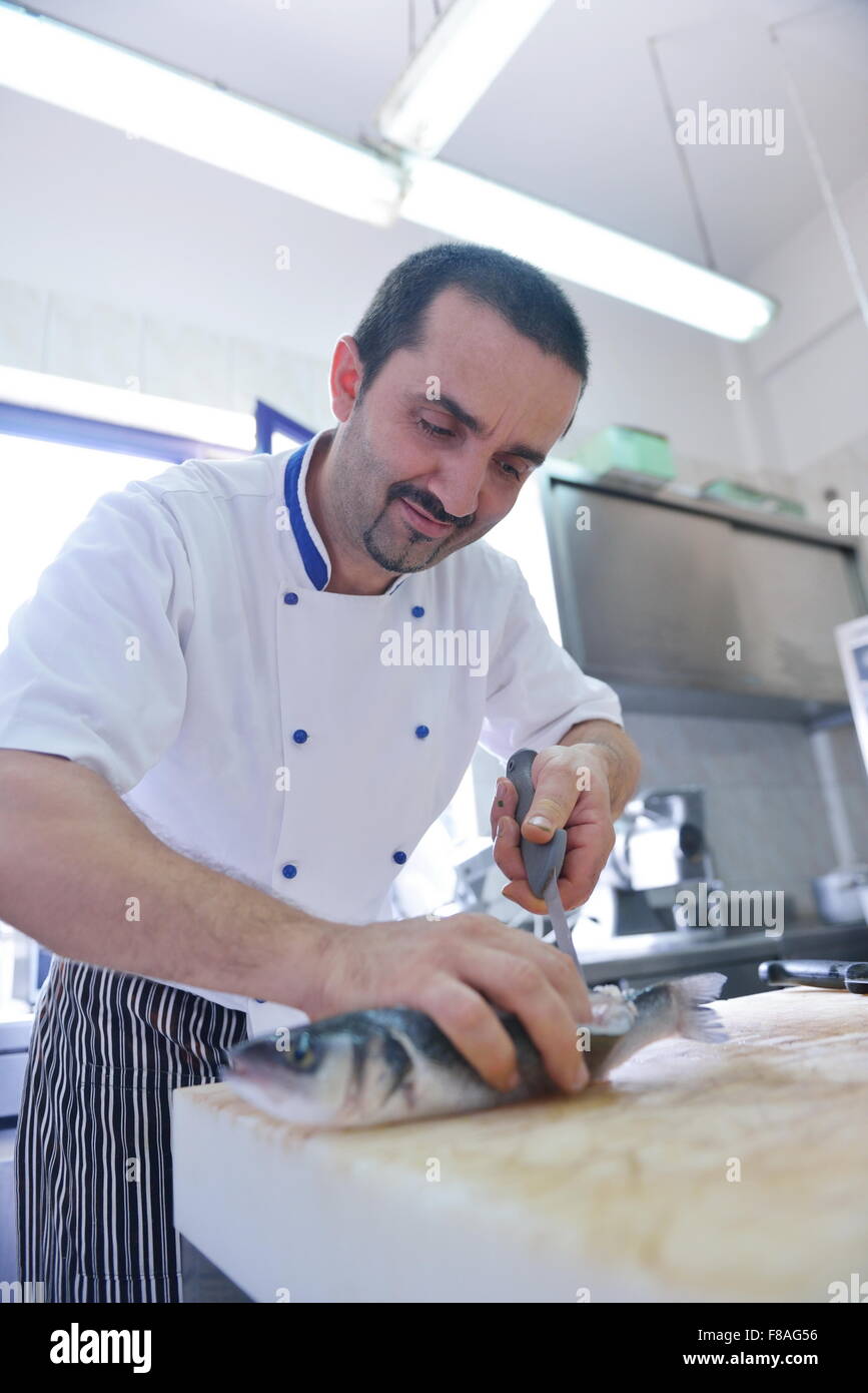 Handsome chef dressed in white uniform decorating pasta salad and ...