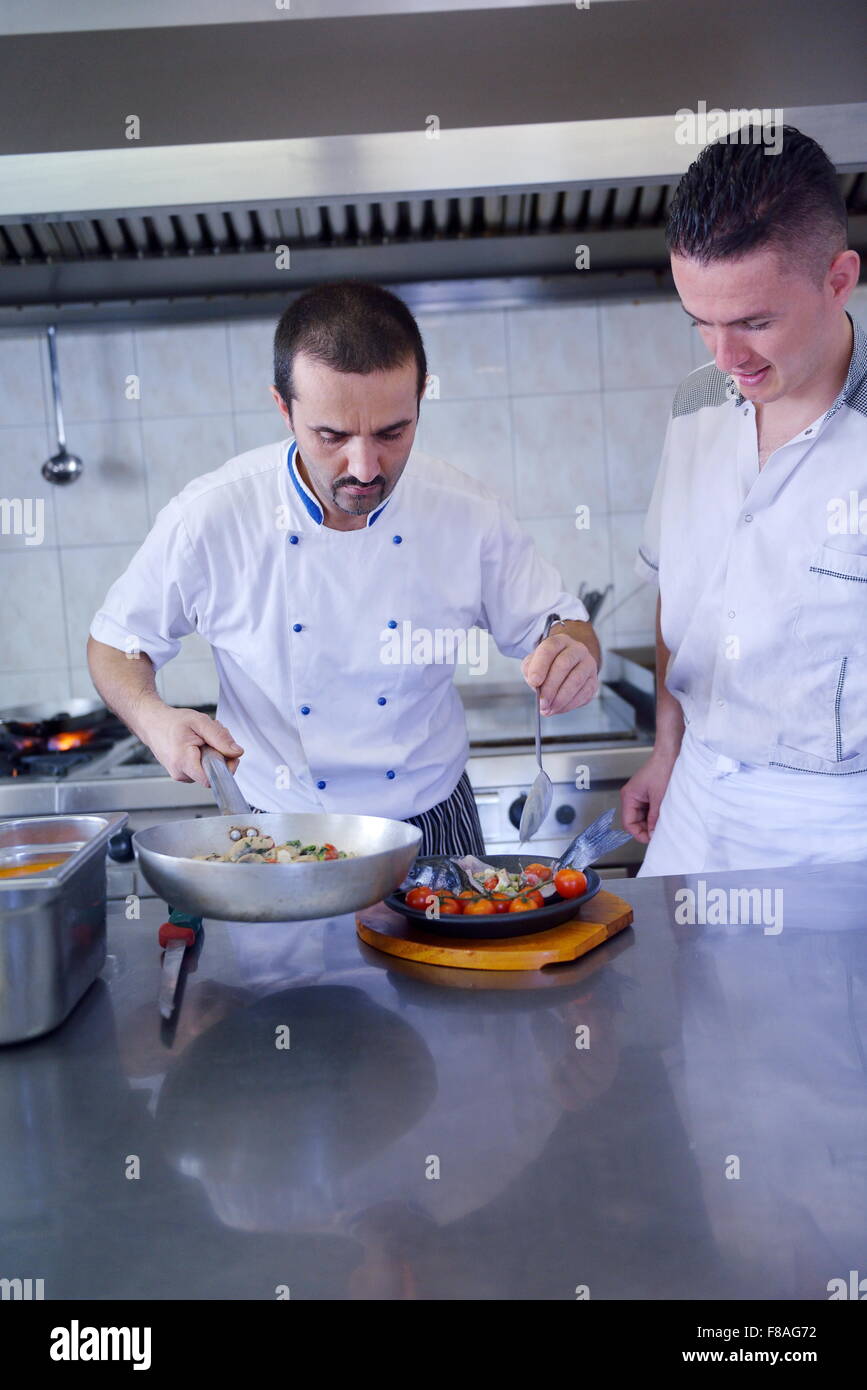 Handsome chef dressed in white uniform decorating pasta salad and ...