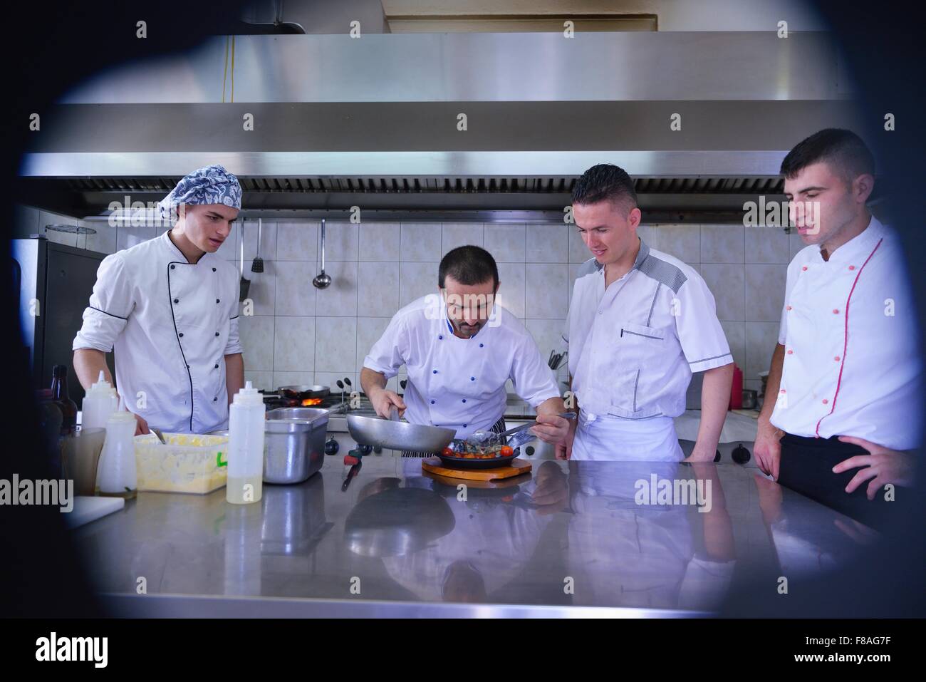 Handsome chef dressed in white uniform decorating pasta salad and ...
