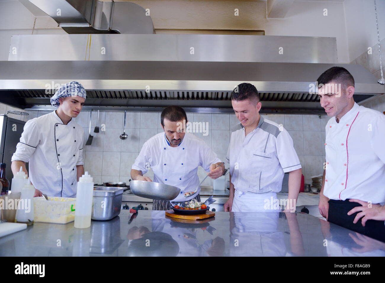 Handsome chef dressed in white uniform decorating pasta salad and ...