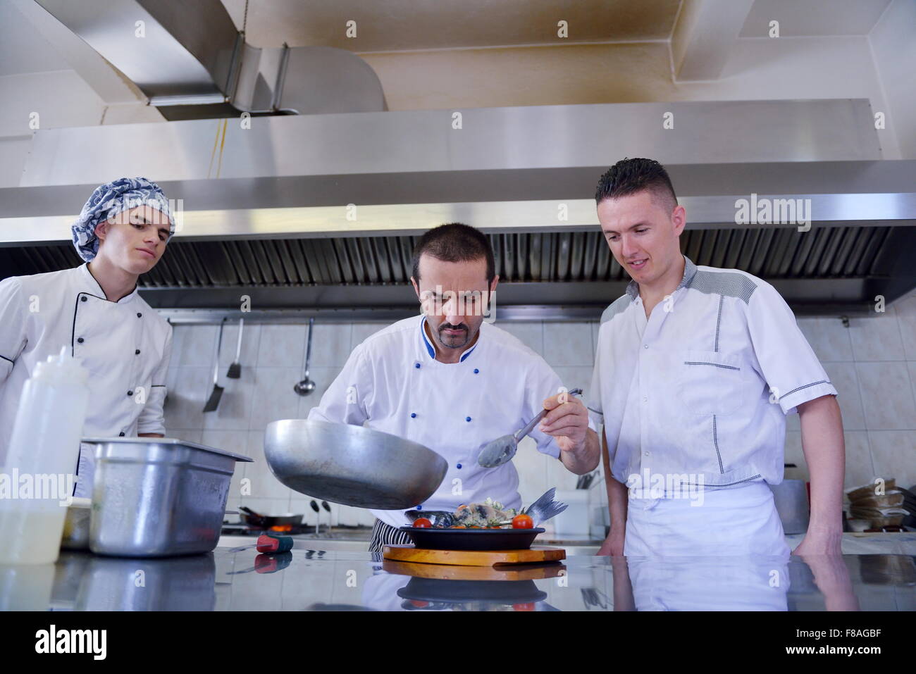 Handsome chef dressed in white uniform decorating pasta salad and ...