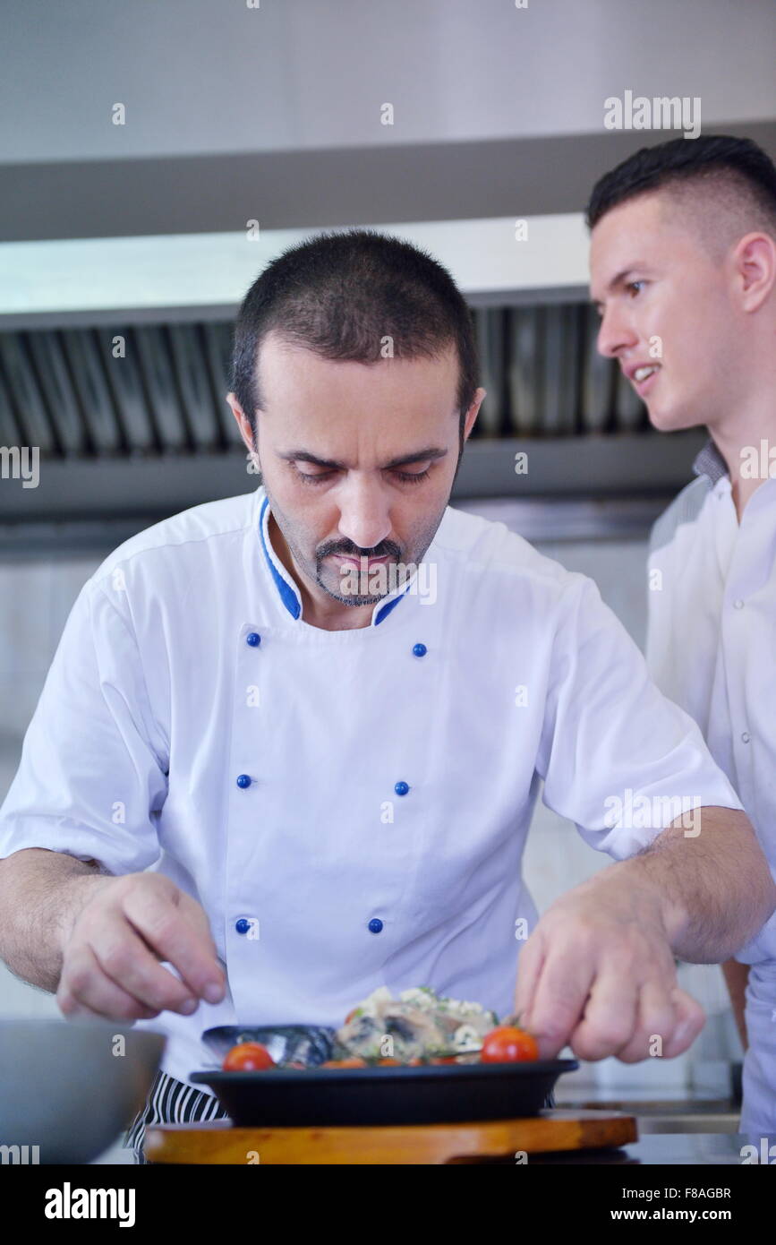 Handsome chef dressed in white uniform decorating pasta salad and ...