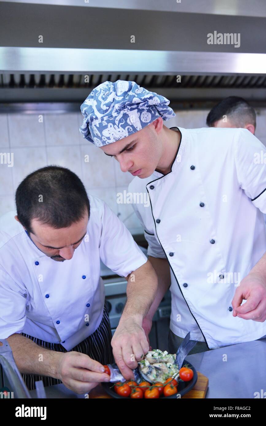 Handsome chef dressed in white uniform decorating pasta salad and ...