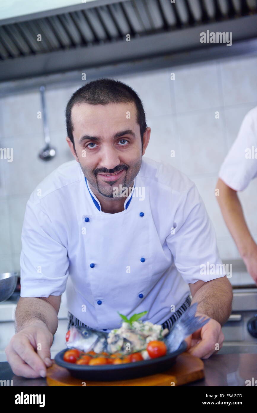 Handsome chef dressed in white uniform decorating pasta salad and ...