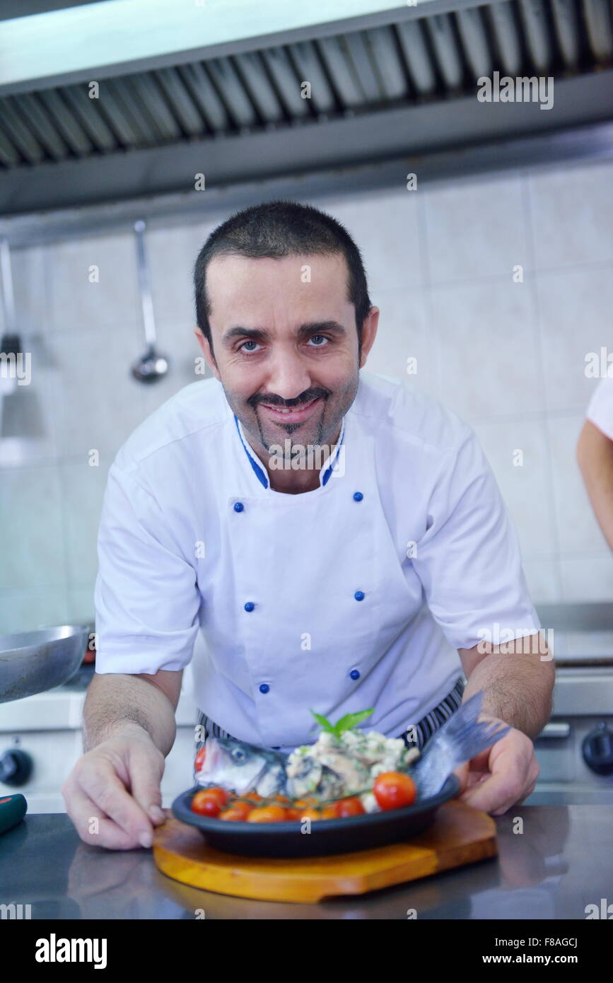 Handsome chef dressed in white uniform decorating pasta salad and ...