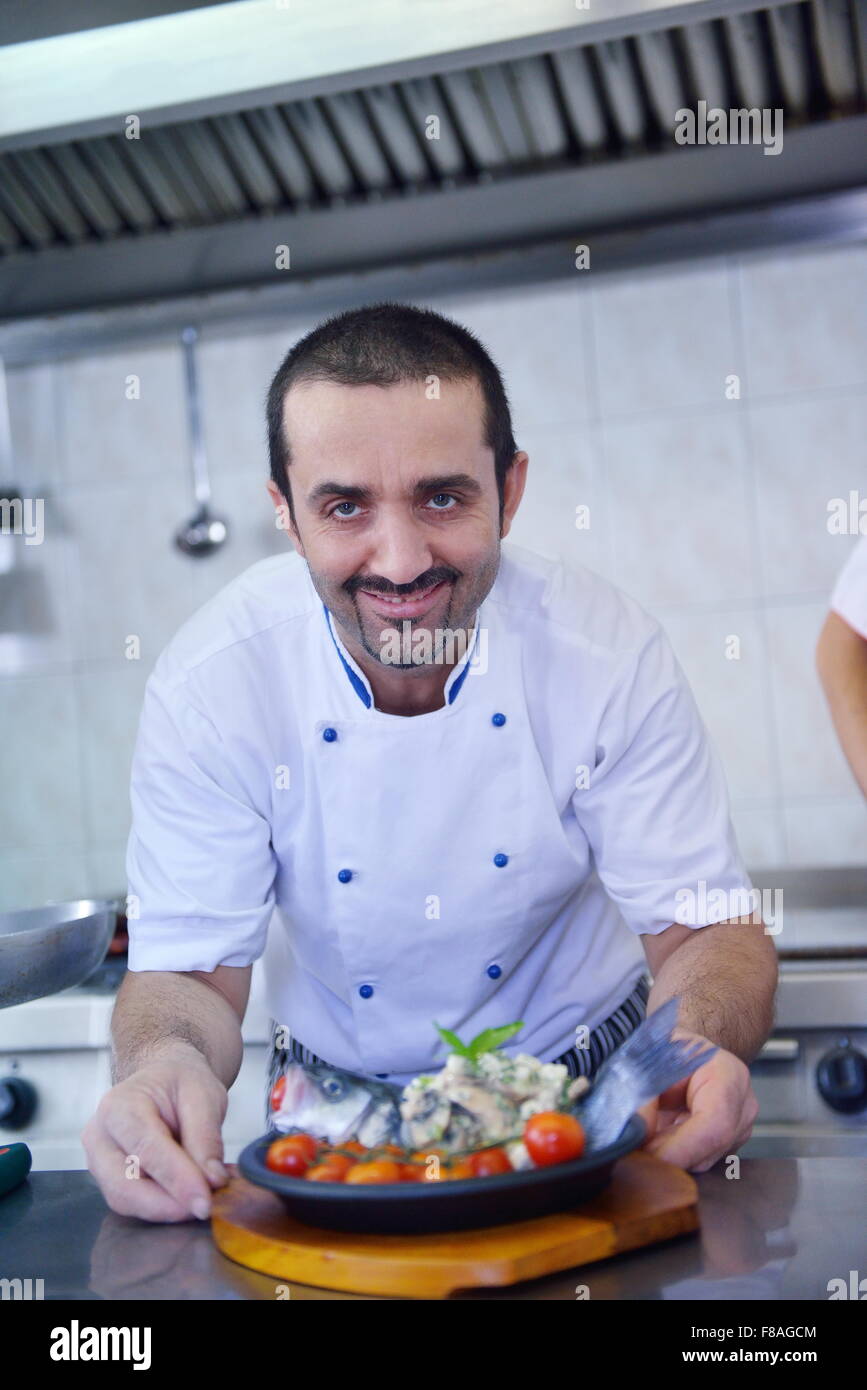 Handsome chef dressed in white uniform decorating pasta salad and ...