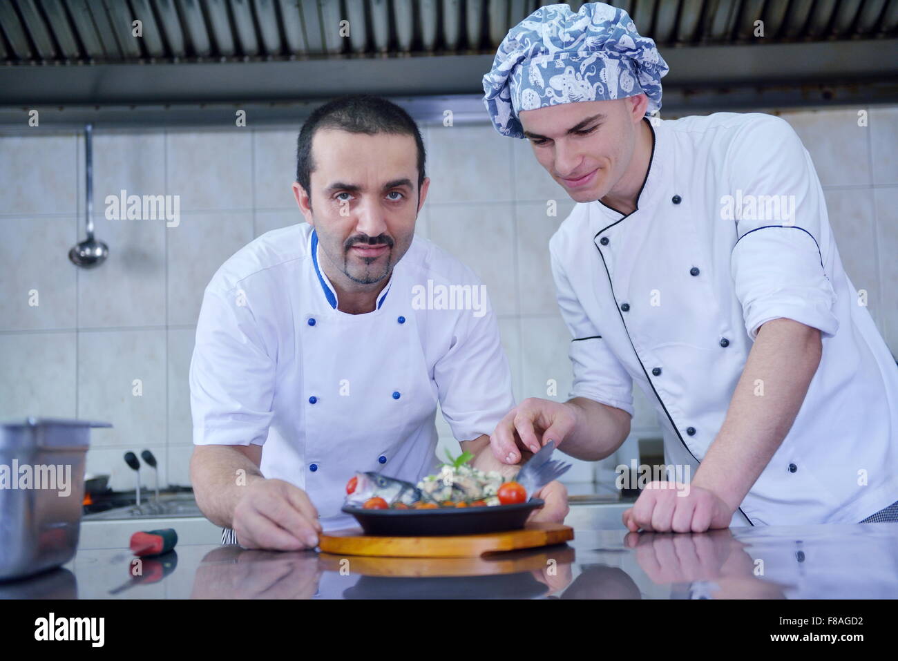 Handsome chef dressed in white uniform decorating pasta salad and ...