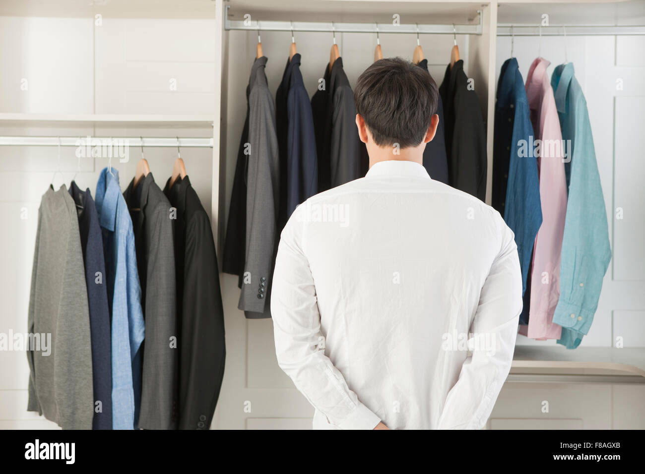 Back appearance of a man looking at his closet with his hands behind ... Back appearance of a man looking at his closet with his hands behind ...