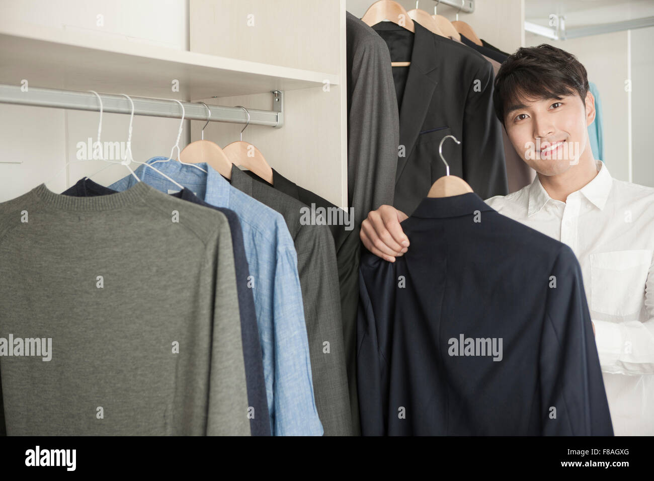 Man standing near the closet and holding a business jacket Stock Photo ...