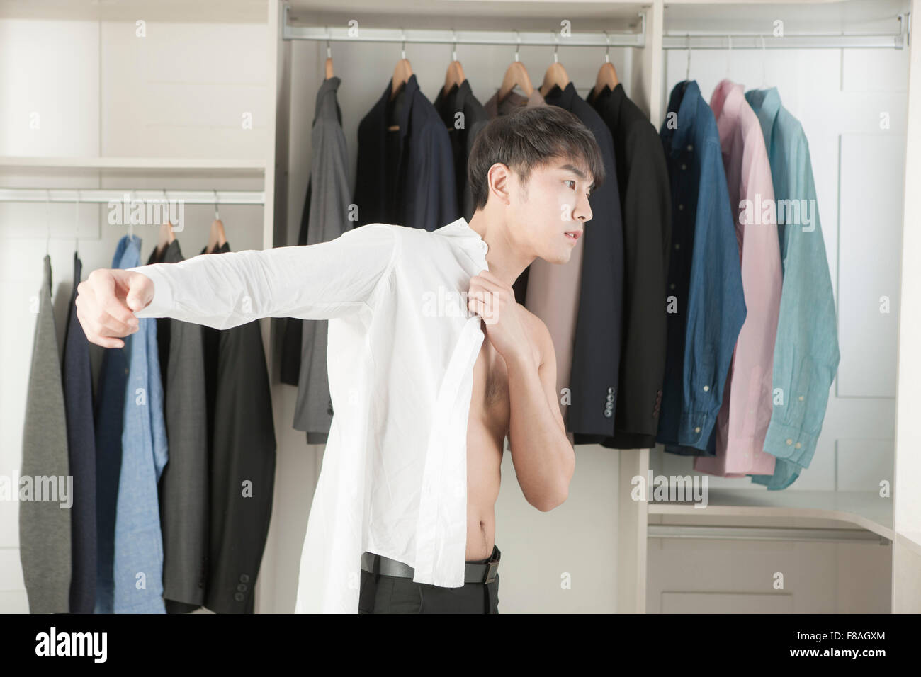 Man putting on his shirt in dressing room Stock Photo - Alamy