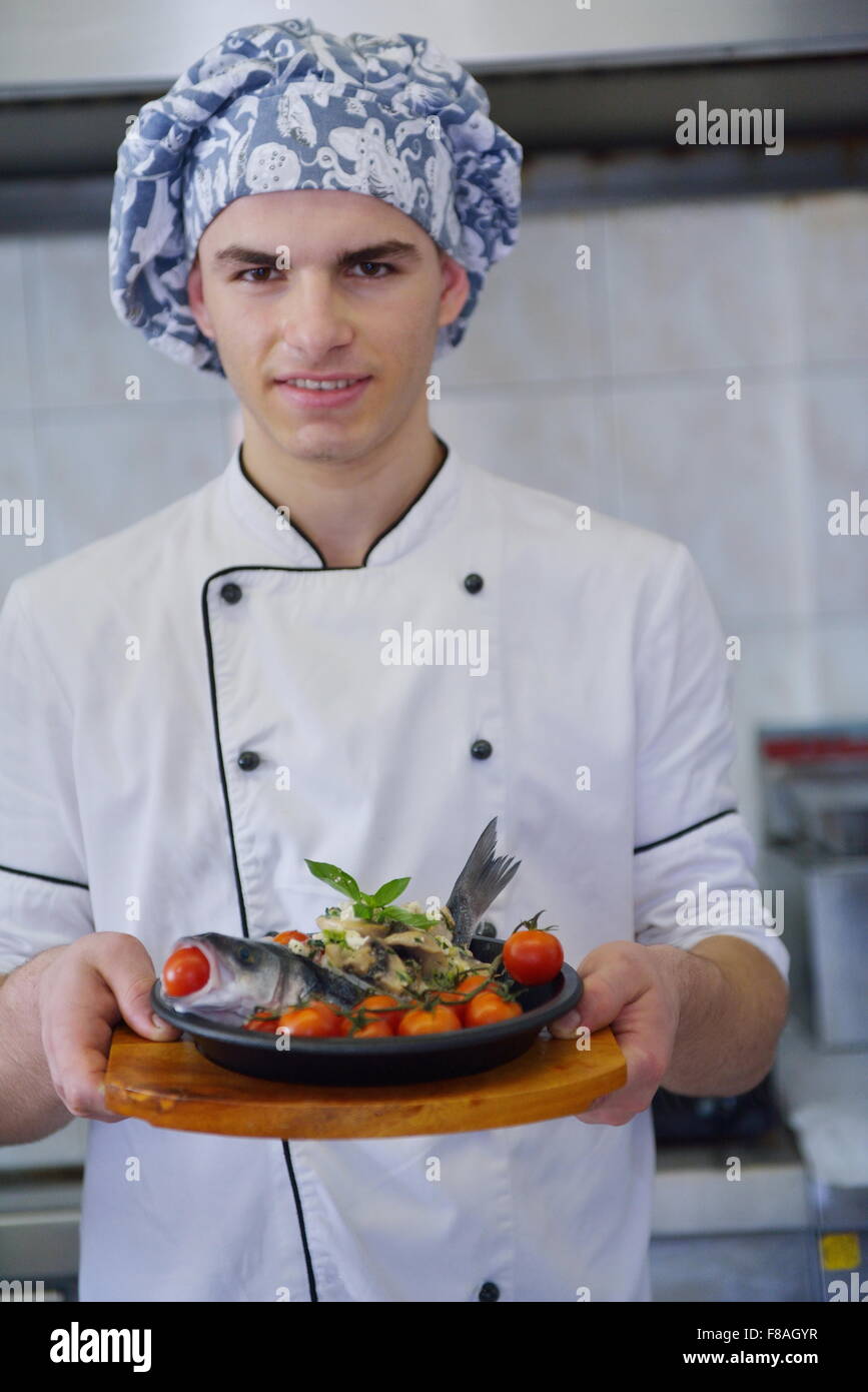 Handsome chef dressed in white uniform decorating pasta salad and ...