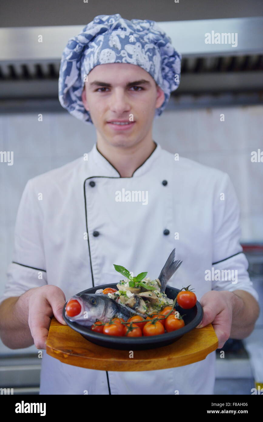 Handsome chef dressed in white uniform decorating pasta salad and ...