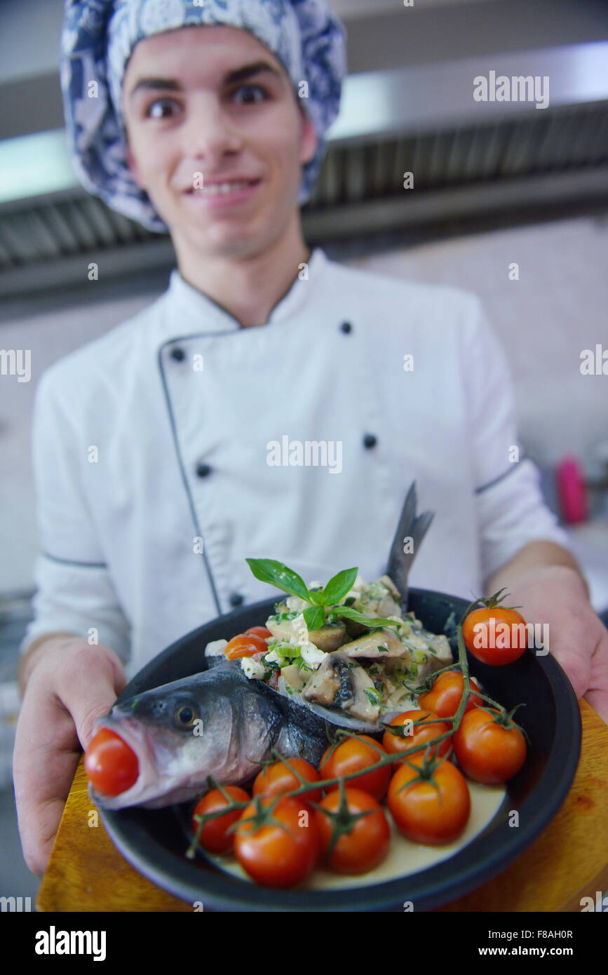 Handsome chef dressed in white uniform decorating pasta salad and ...