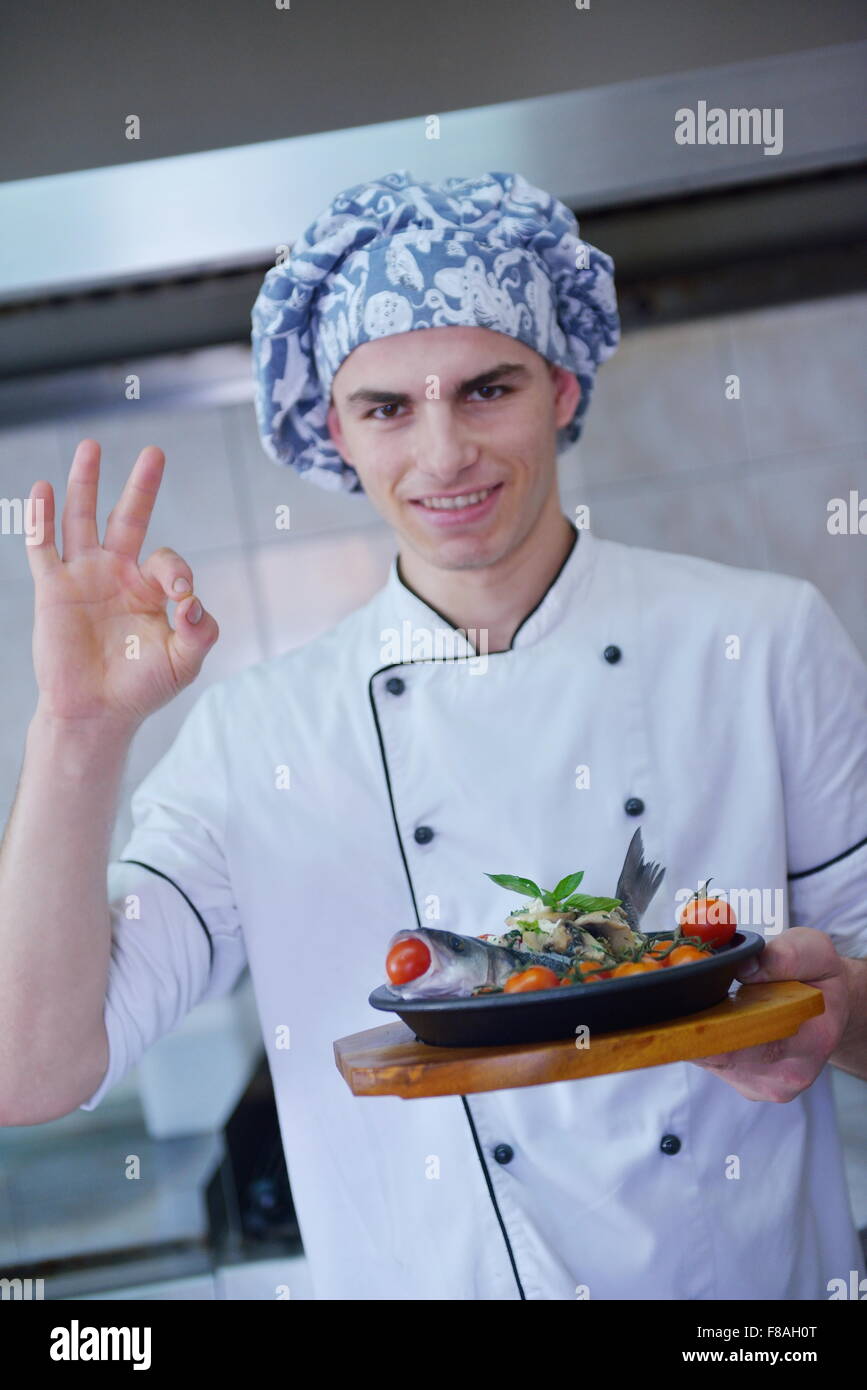 Handsome chef dressed in white uniform decorating pasta salad and ...