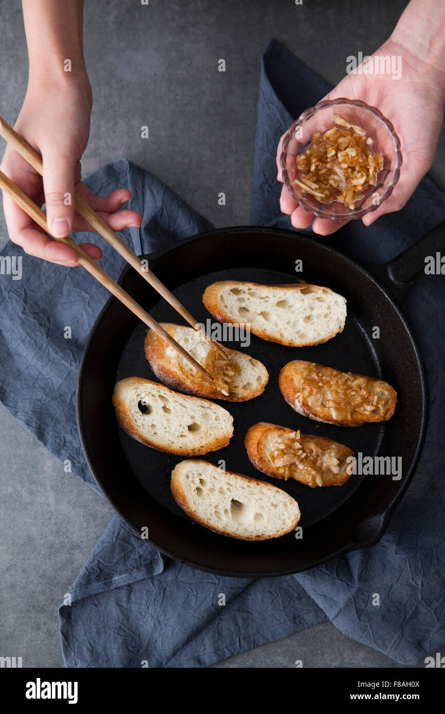 Garnish being placed on the slices of baguette in the pan Stock Photo ...