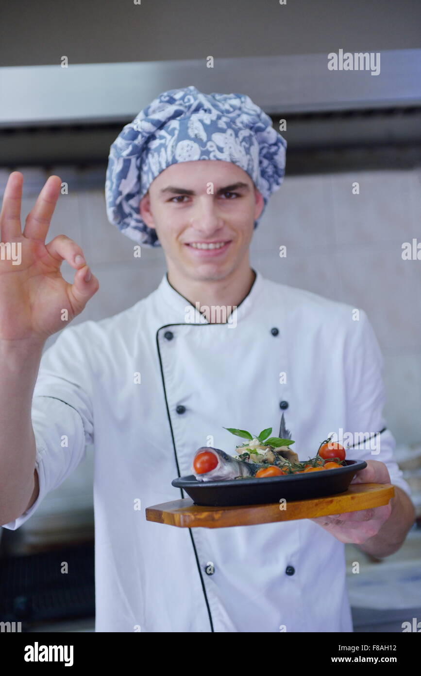 Handsome chef dressed in white uniform decorating pasta salad and ...