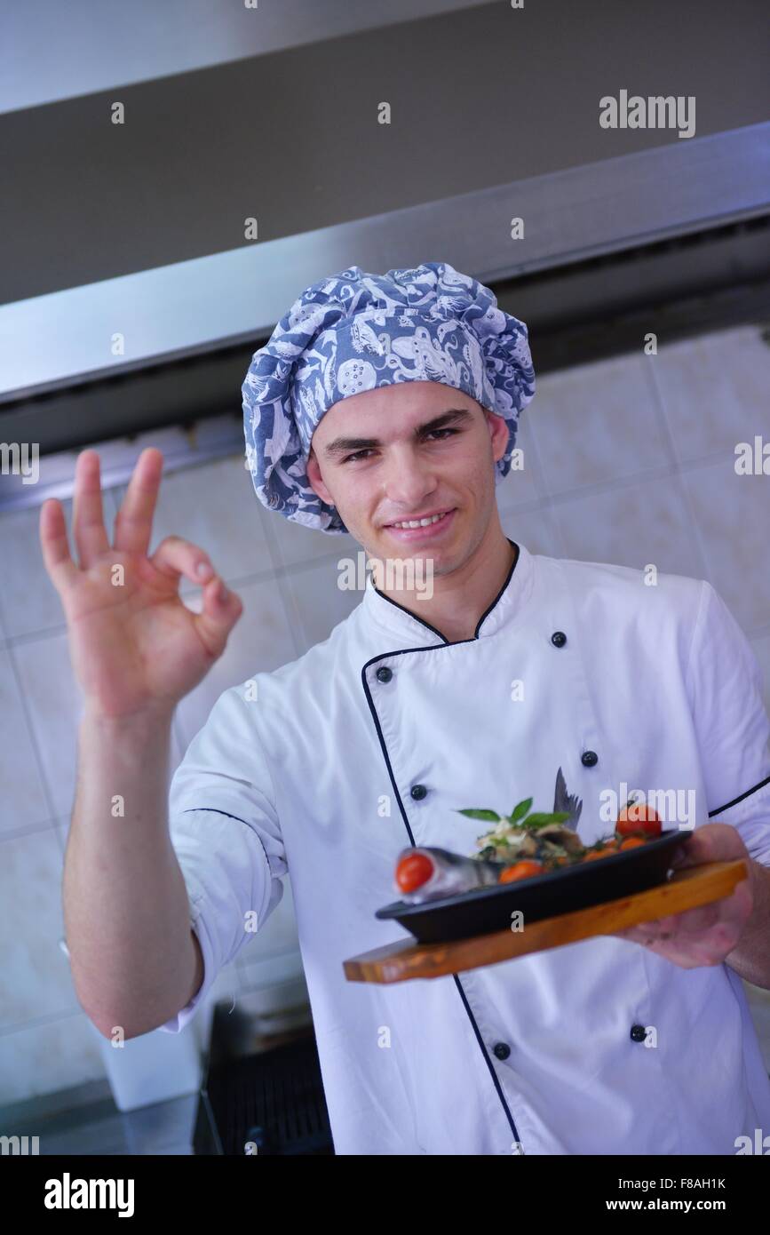 Handsome chef dressed in white uniform decorating pasta salad and ...