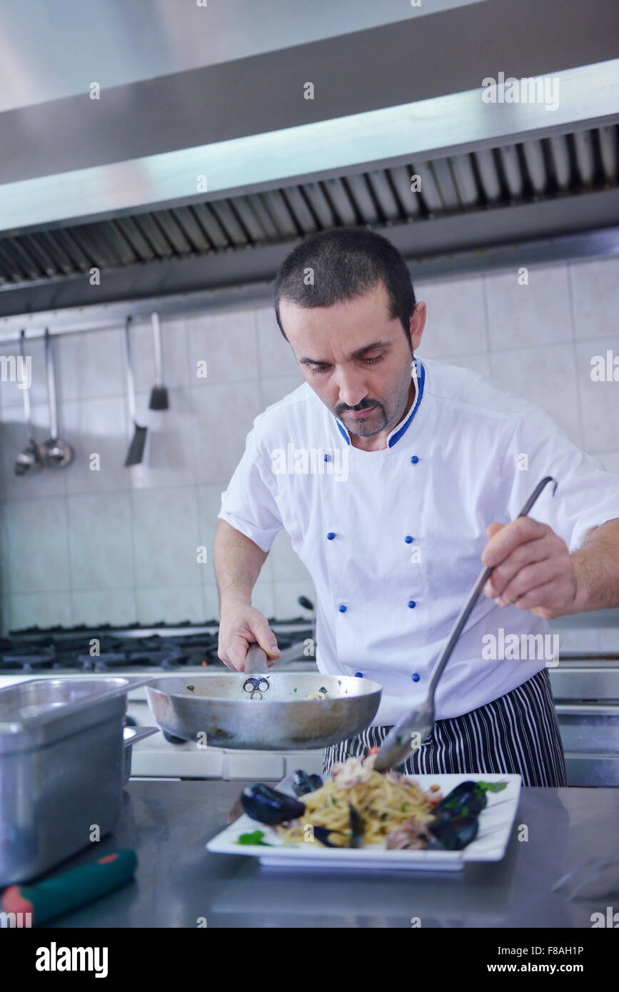 Handsome chef dressed in white uniform decorating pasta salad and ...