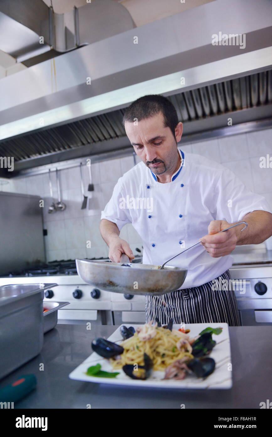 Handsome chef dressed in white uniform decorating pasta salad and ...