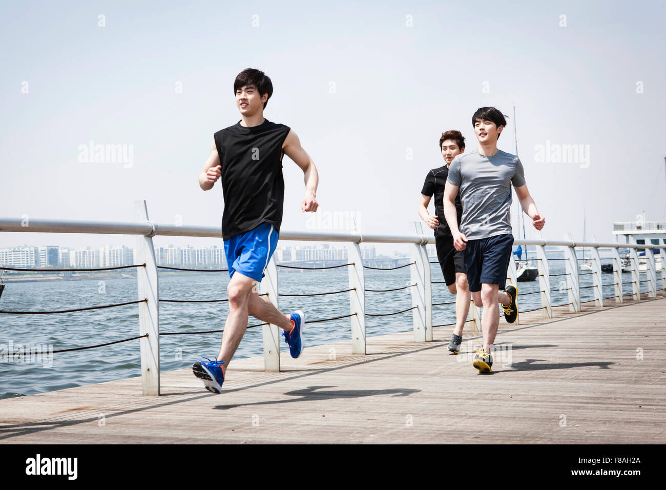 Three men in sportswear running along the road at the park near the Han ...