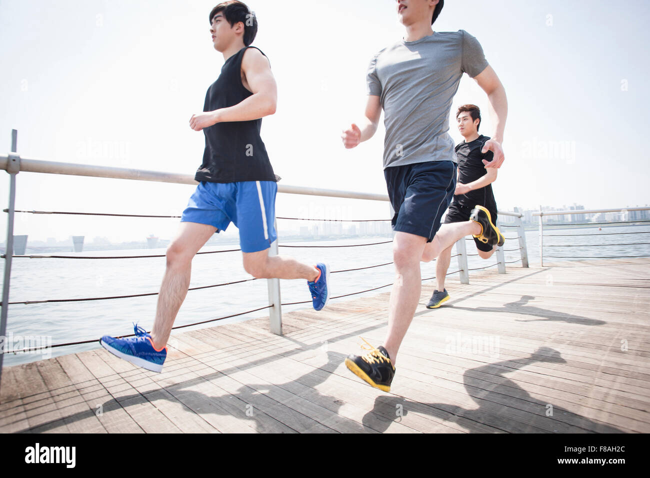 Three men in sportswear running along the road at the park near the Han ...