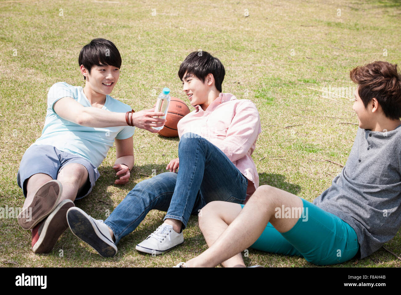 Three men leaning back on the grass at the park Stock Photo - Alamy