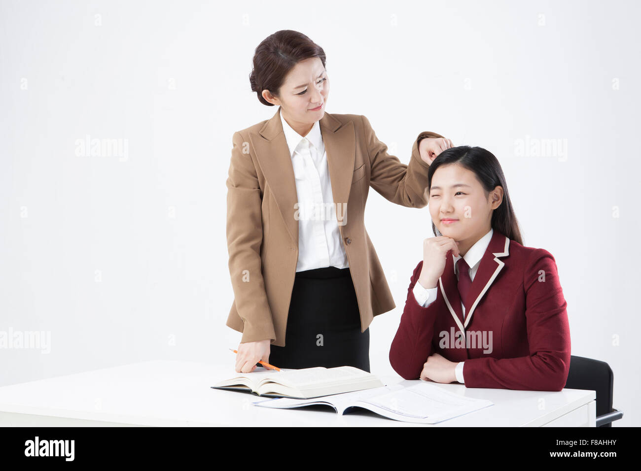 High school girl seated at the desk with open books and the teacher ...