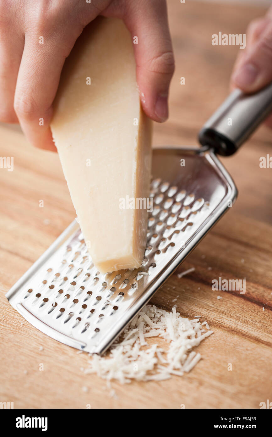 Chunk of cheese being shredded with a grater Stock Photo - Alamy