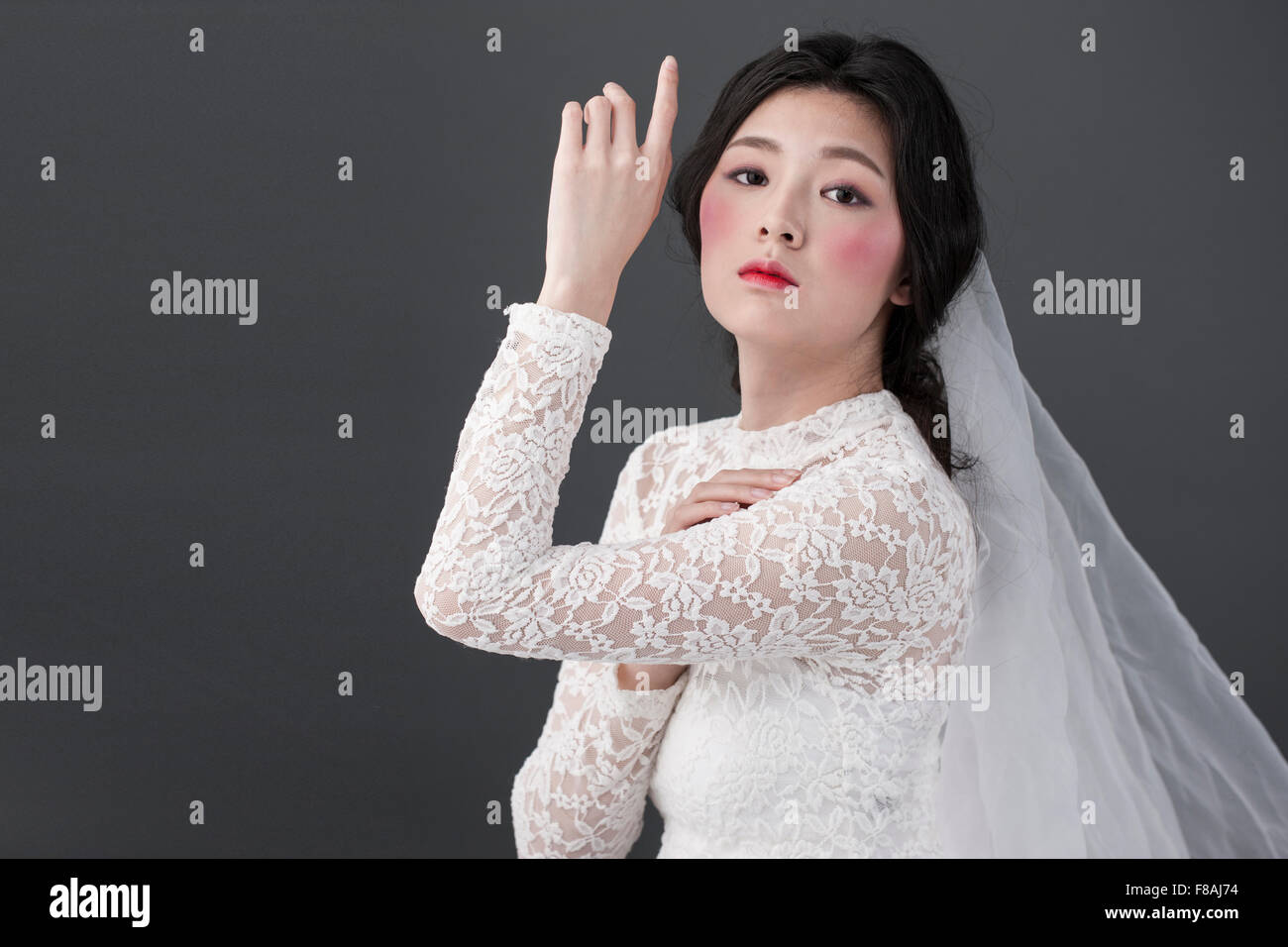 Asian woman in white lace dress and lace veil with pink blush make-up ...