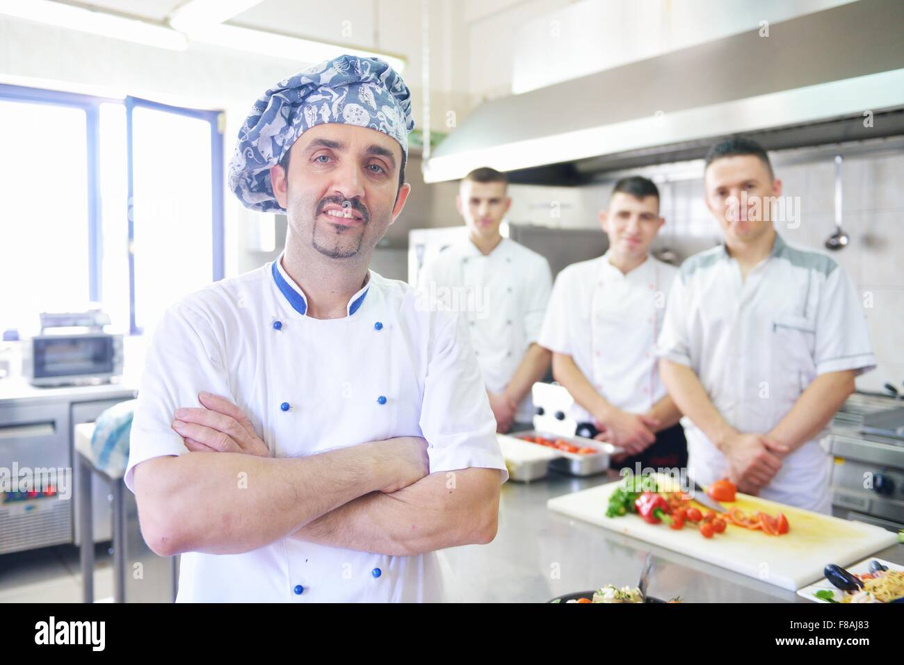 Handsome chef dressed in white uniform decorating pasta salad and ...