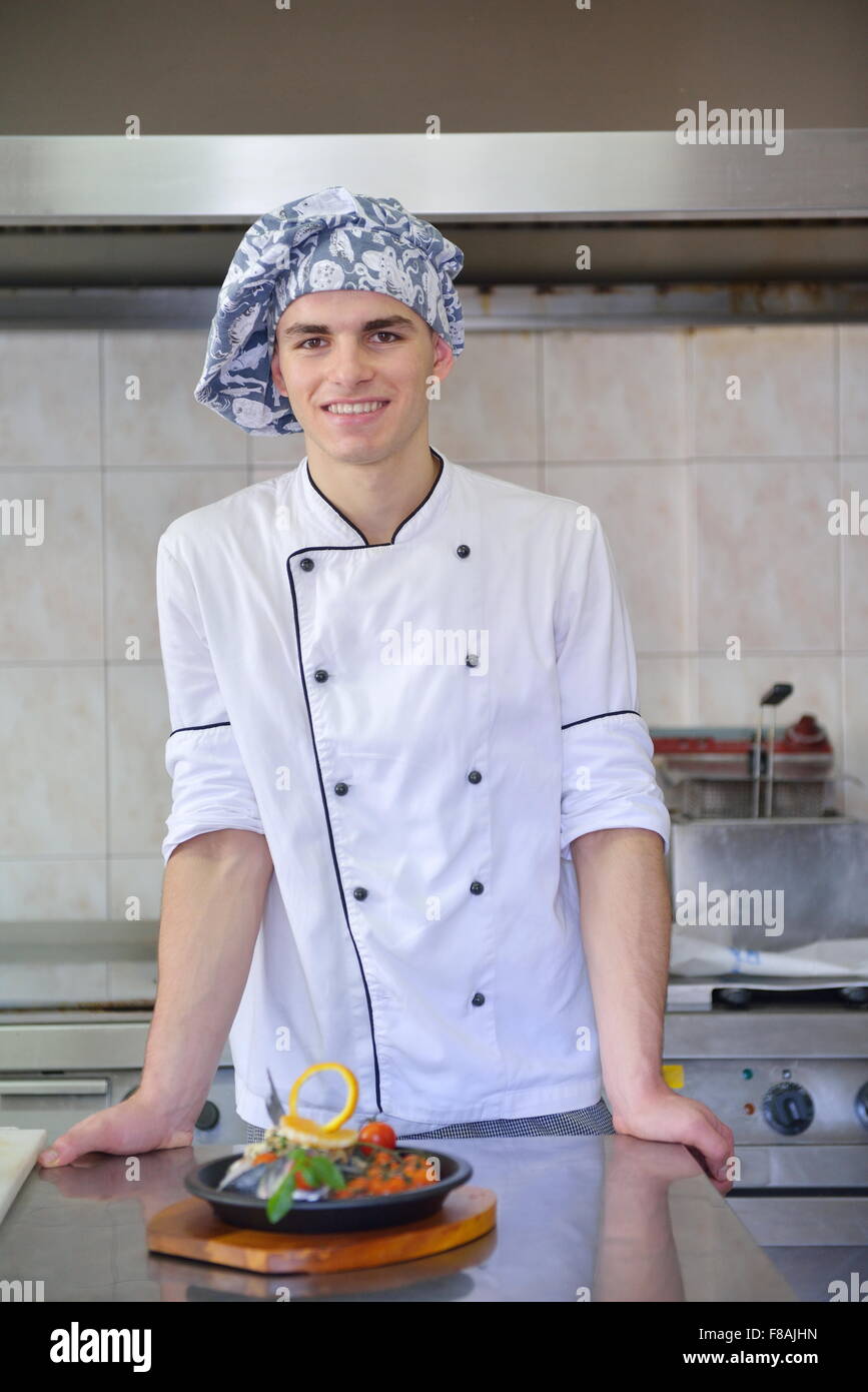 Handsome chef dressed in white uniform decorating pasta salad and ...