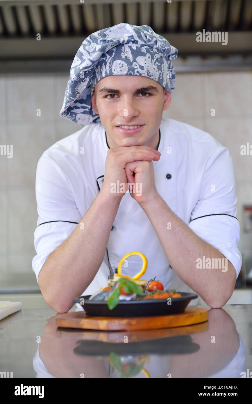Handsome chef dressed in white uniform decorating pasta salad and ...