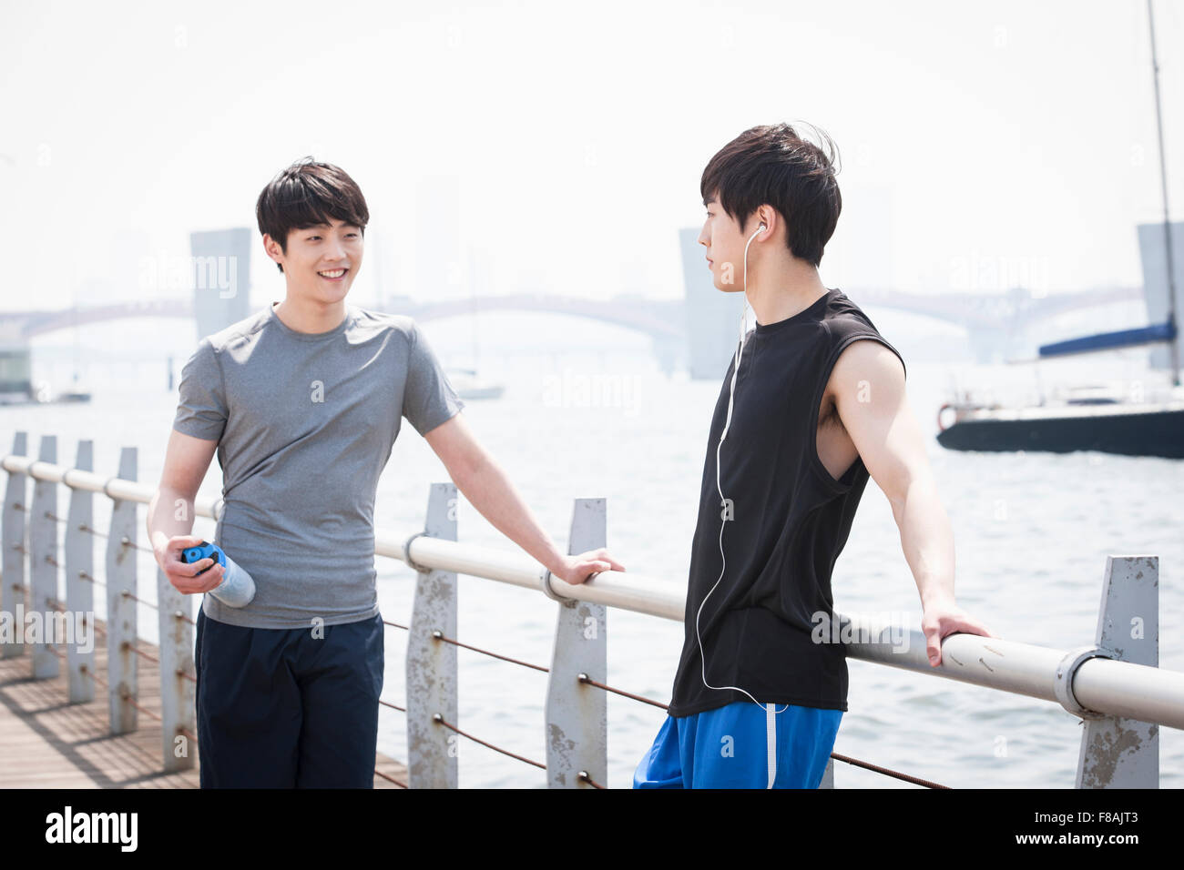 Two young men leaning on the fence of the riverside at Han river park ...