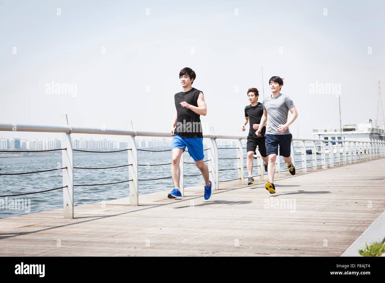 Three young men in sportswear running along the riverside at the Han ...