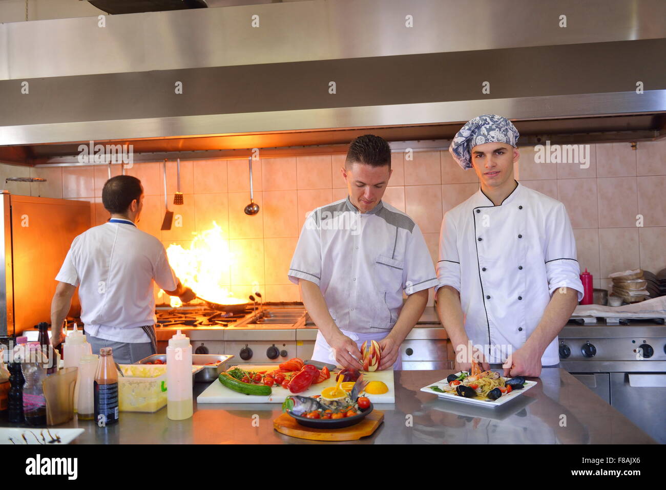 Handsome chef dressed in white uniform decorating pasta salad and ...