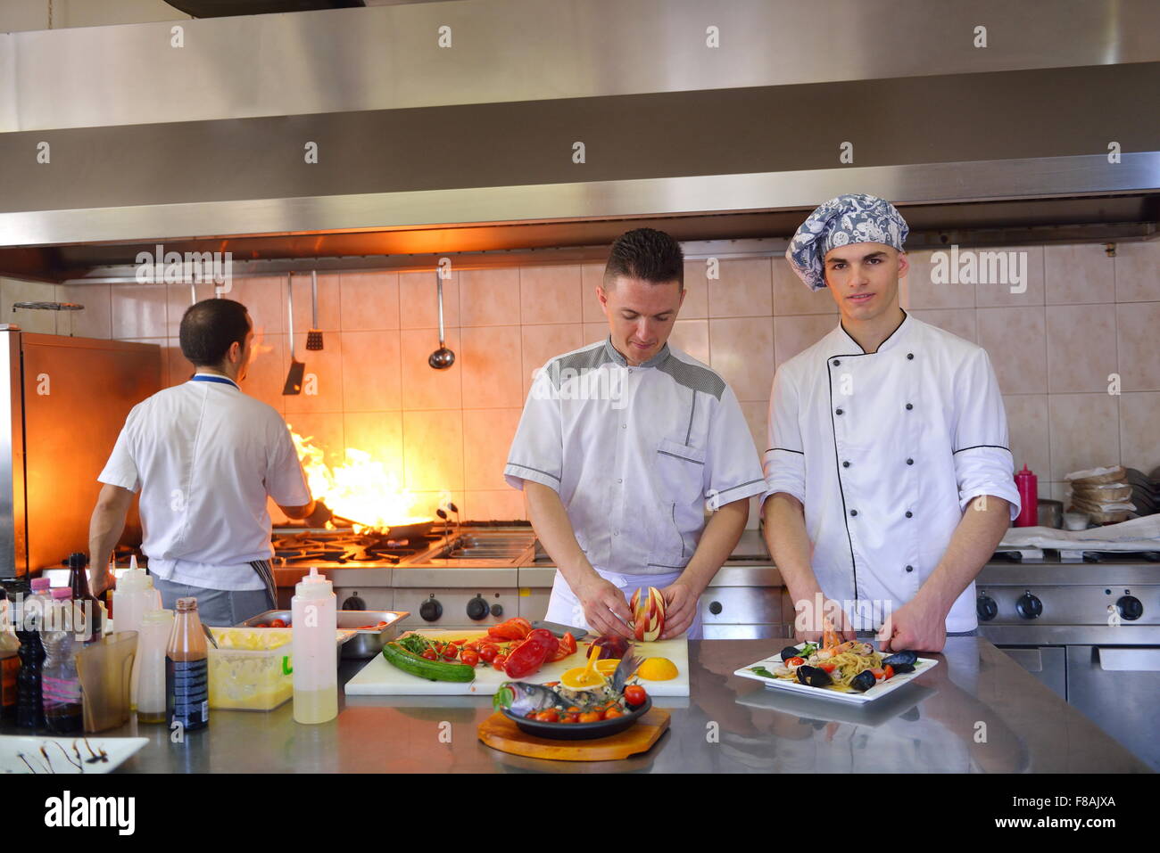 Handsome chef dressed in white uniform decorating pasta salad and ...