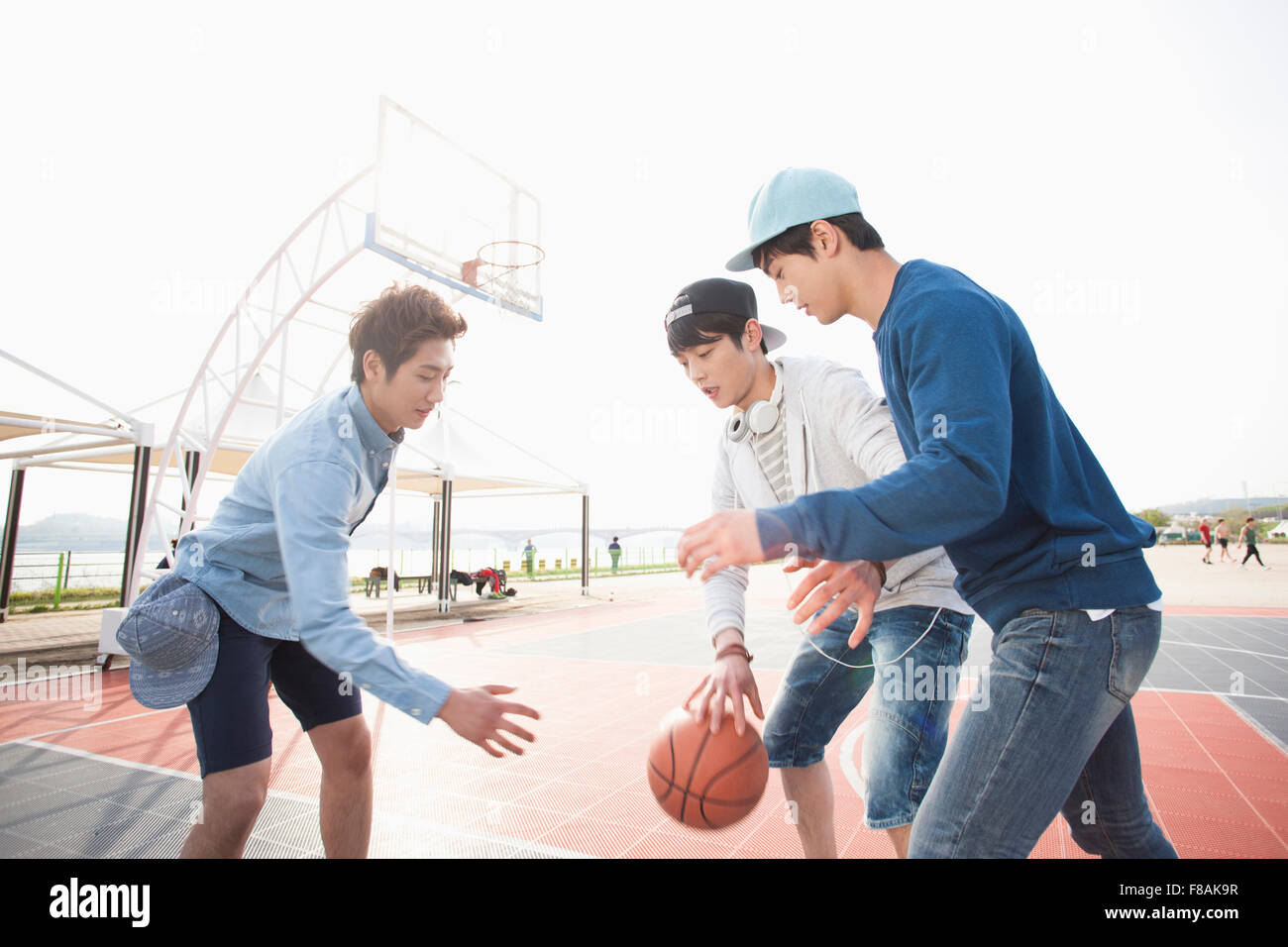 Three young men playing basketball at the court and facing each other ...