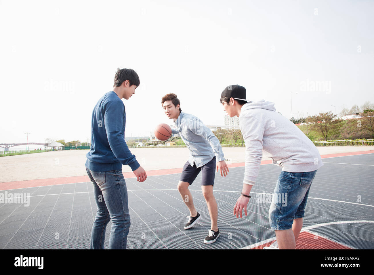 Three young men looking down and playing basketball at the court ...
