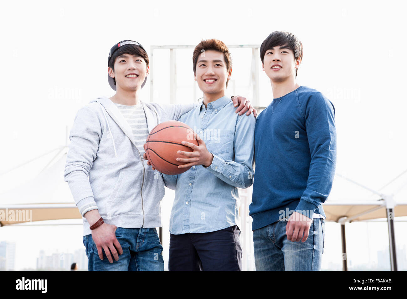 Three young men standing at the basketball court staring upward Stock ...