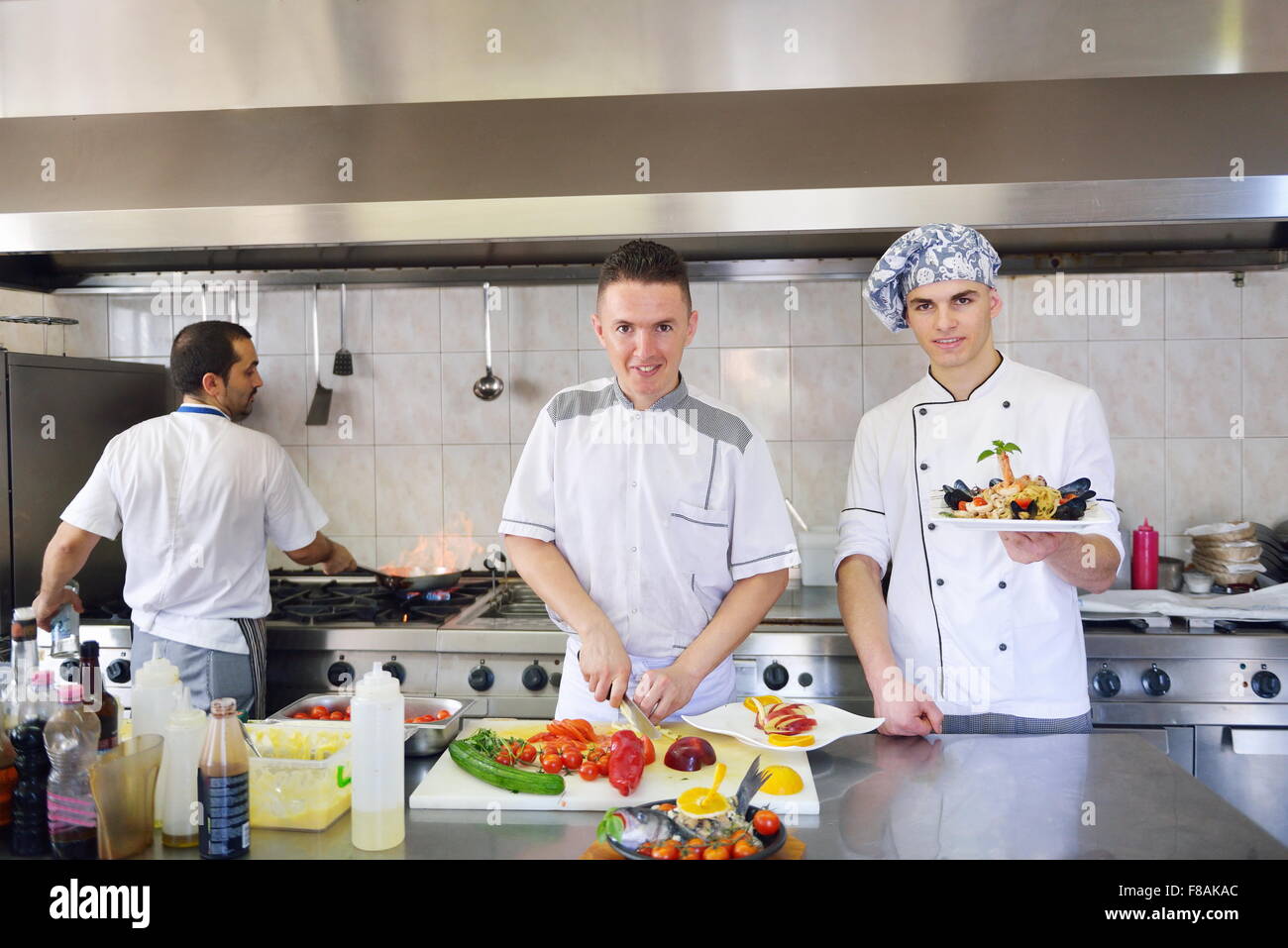 Handsome chef dressed in white uniform decorating pasta salad and ...