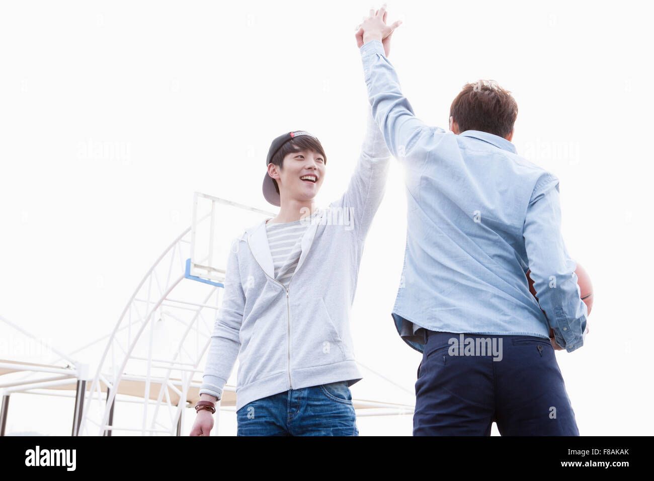 Low angle of two men giving a high-five to each other at the basketball ...